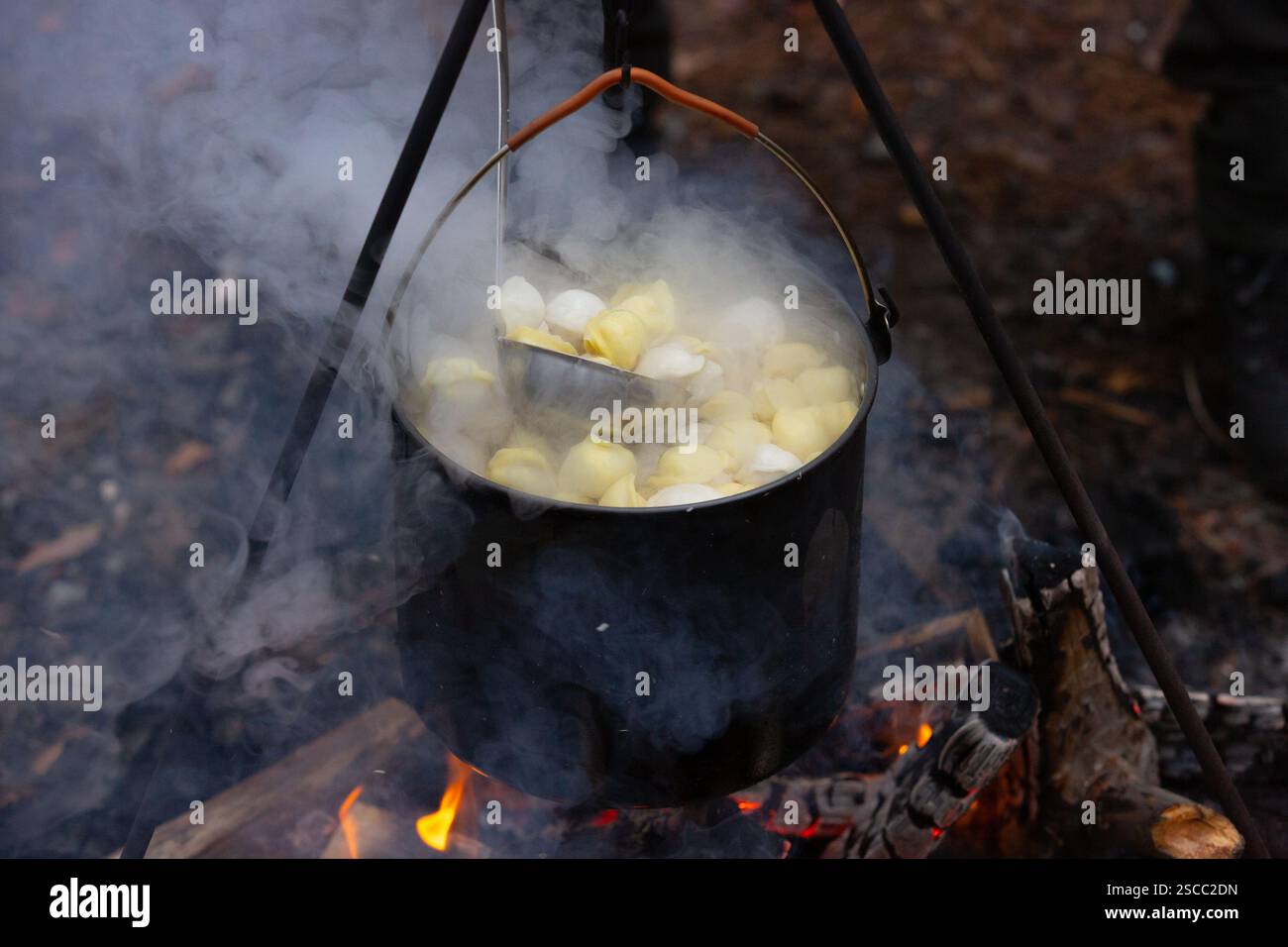 Cooking dumplings in cauldron over fire at campsite Stock Photo - Alamy