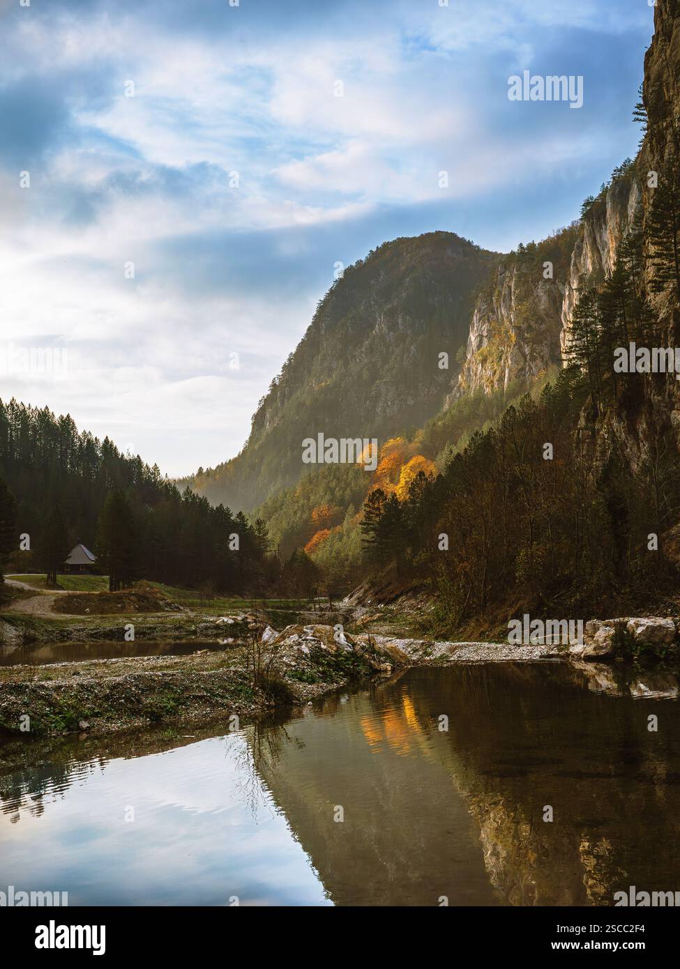 Autumn landscape with a mountain, forest, and a river reflecting fall ...
