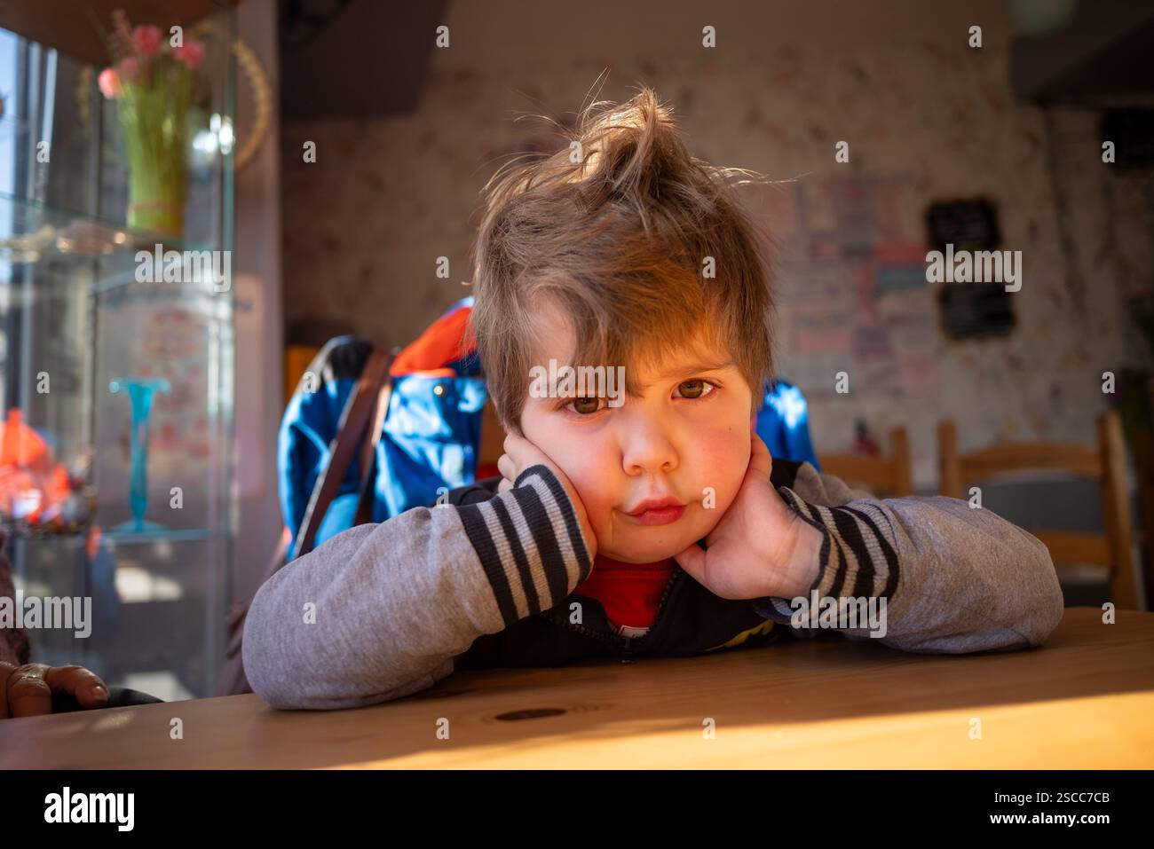 Boy child in a café looking fed up Stock Photo - Alamy