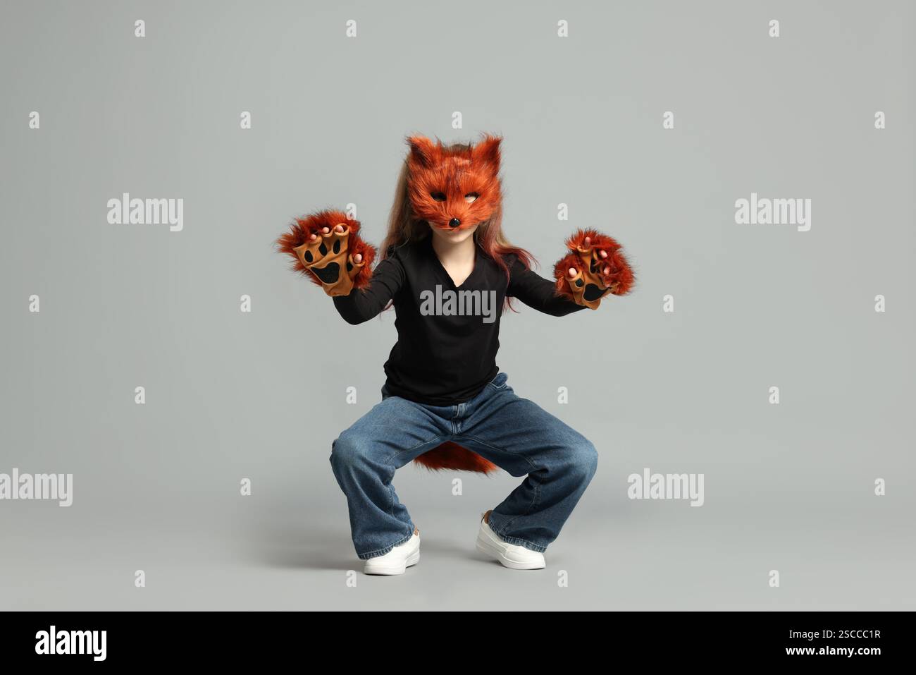 Quadrobics. Girl wearing fox mask, tail and gloves on grey background ...