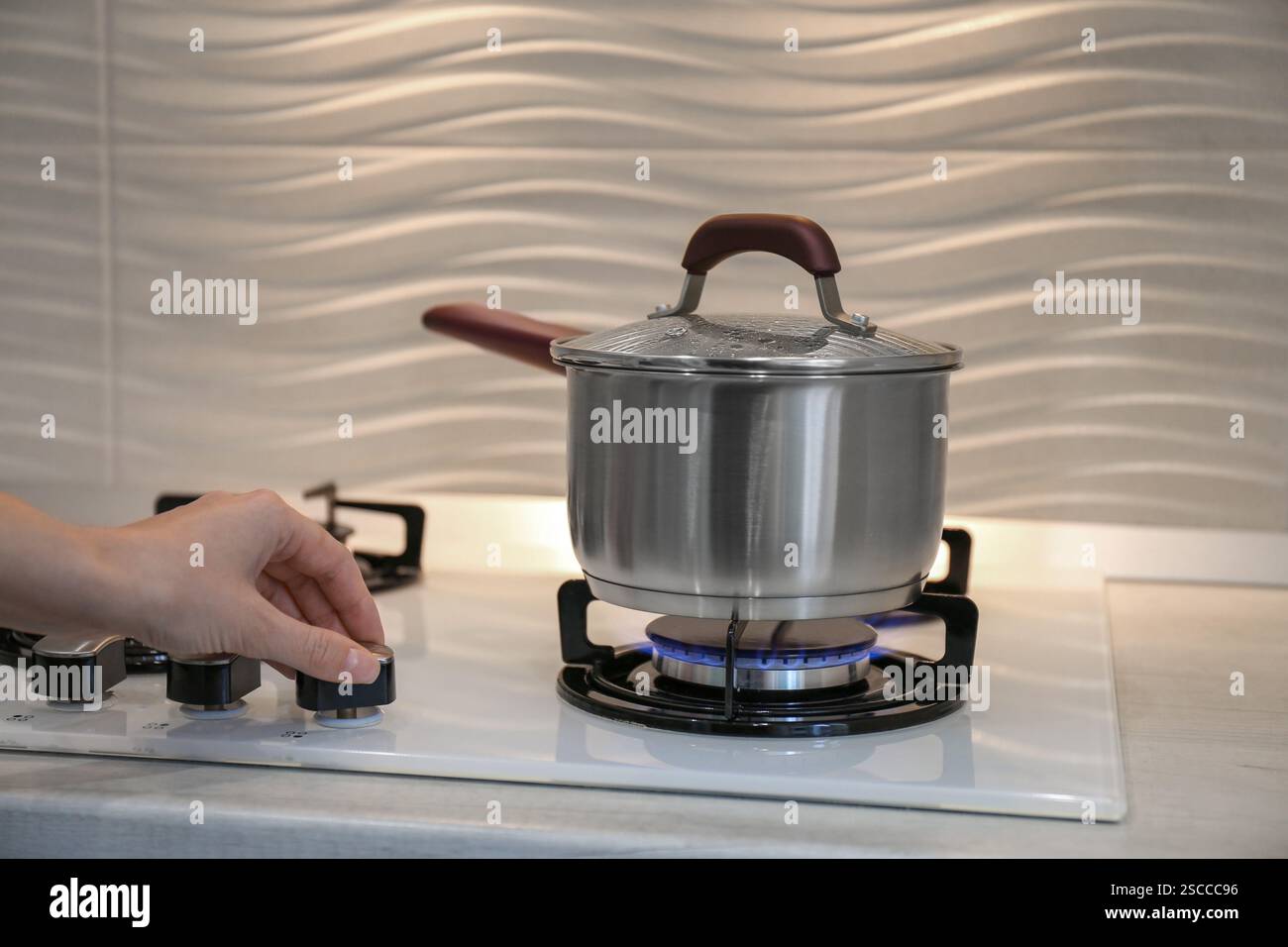 Woman cooking food in pot on modern kitchen stove with burning gas ...