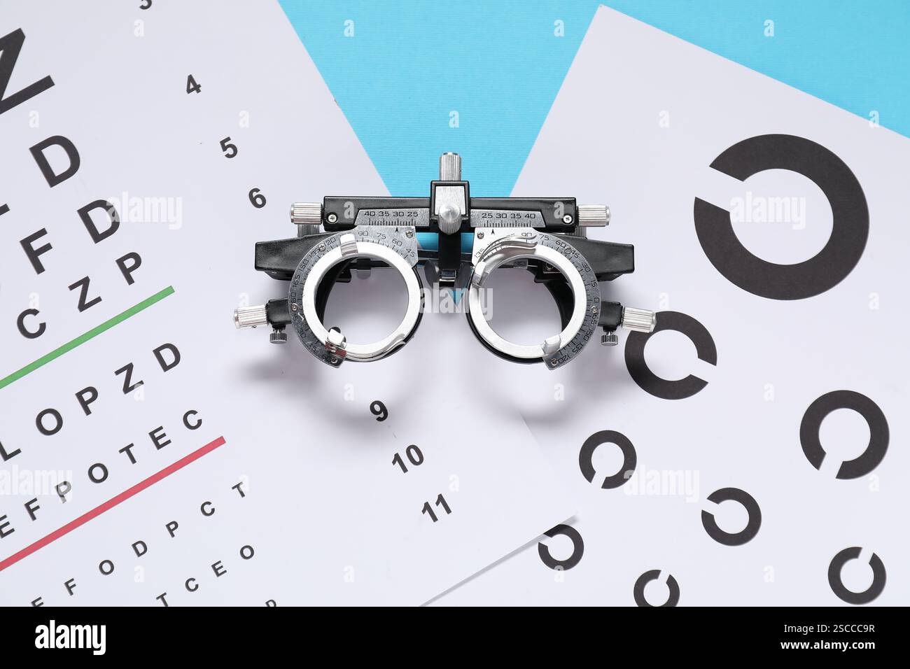 Vision test charts and trial frame on light blue background, top view ...