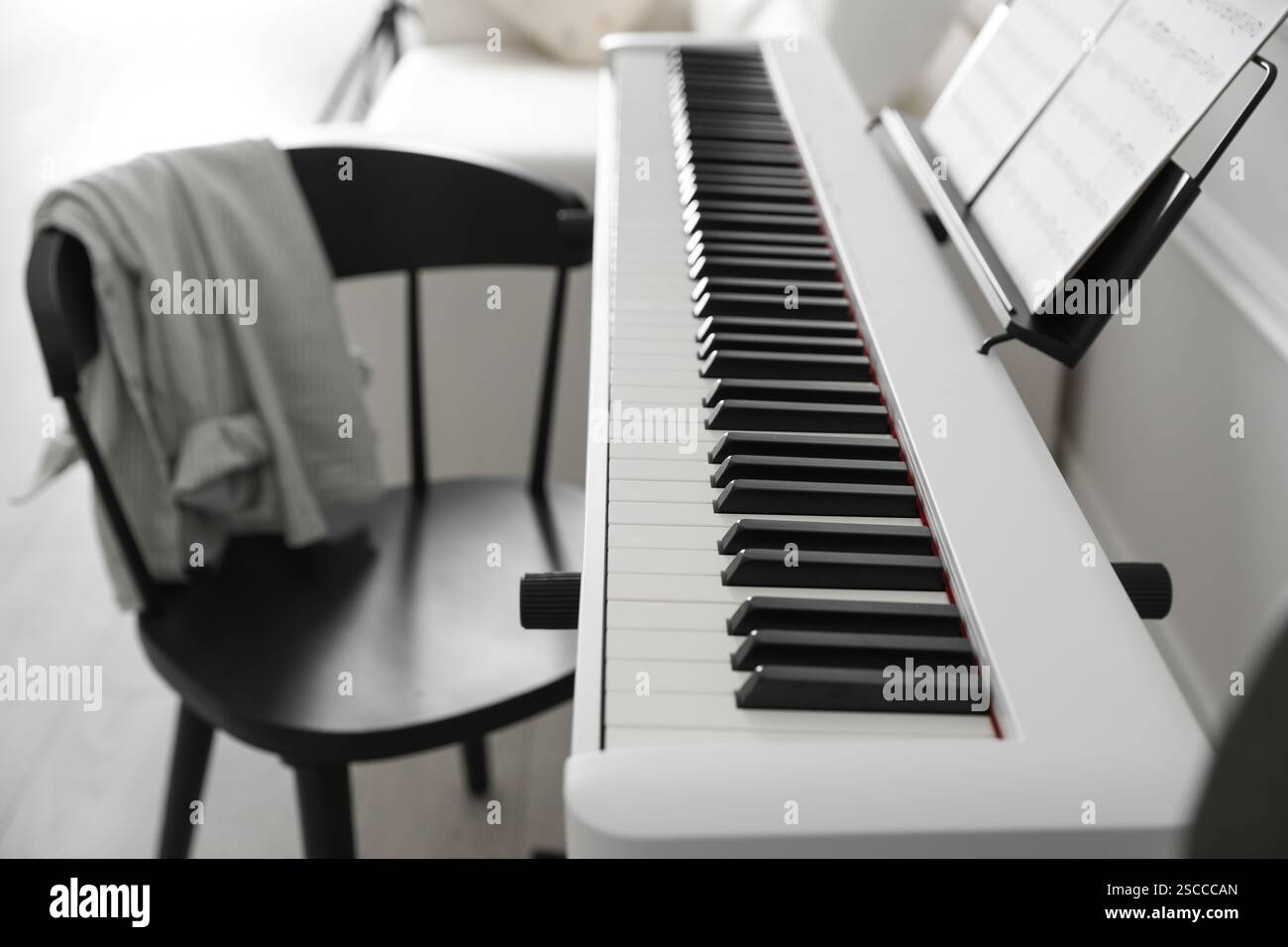 Synthesizer with music sheets and chair at home, closeup Stock Photo ...