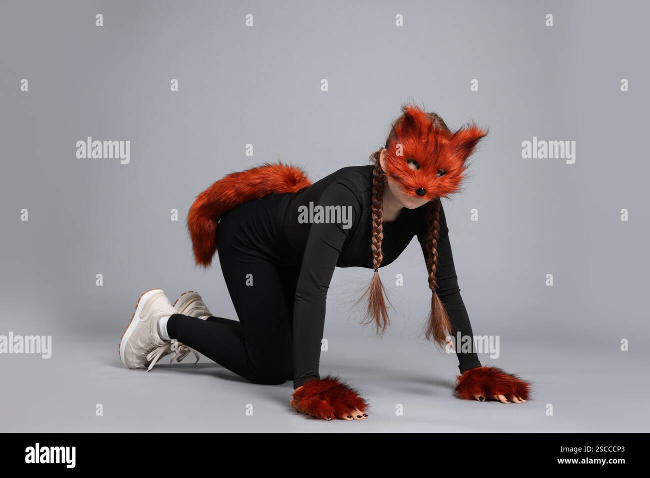 Quadrobics. Girl wearing fox mask, gloves and tail on grey background ...
