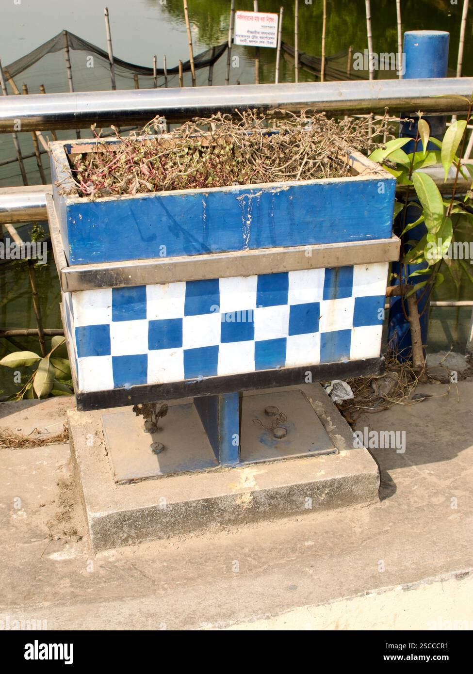 Roadside planter with dried vegetation, painted in a blue-and-white ...
