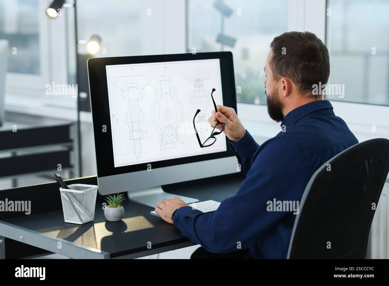 Technician making digital engineering drawing on computer at desk in ...