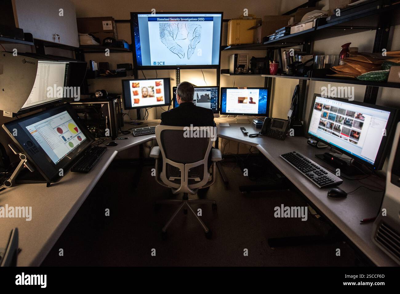 An ICE Cyber Crimes specialist works in a room that is setup to help ...