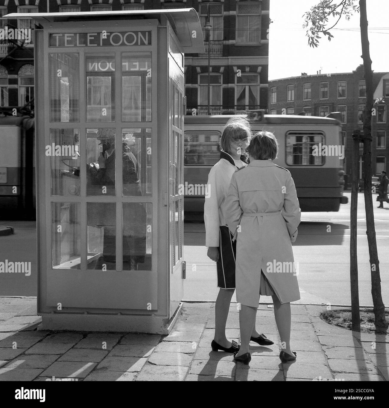 An elderly woman in a telephone box in Amsterdam on the phone and two ...