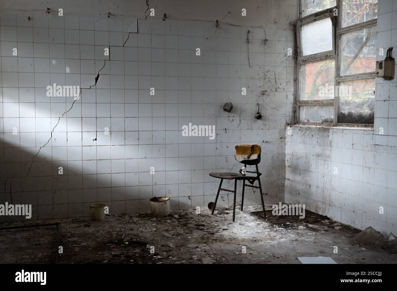 Chair in corner of abandoned kitchen in direct daylight, walls are ...
