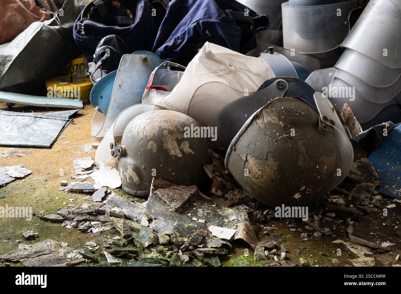 Deserted demining helmets on messy floor in abandoned room, protective ...