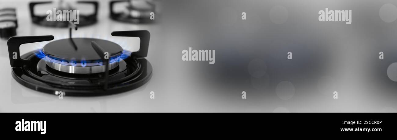 Gas burner with blue flame on stove, closeup. Banner design with space ...