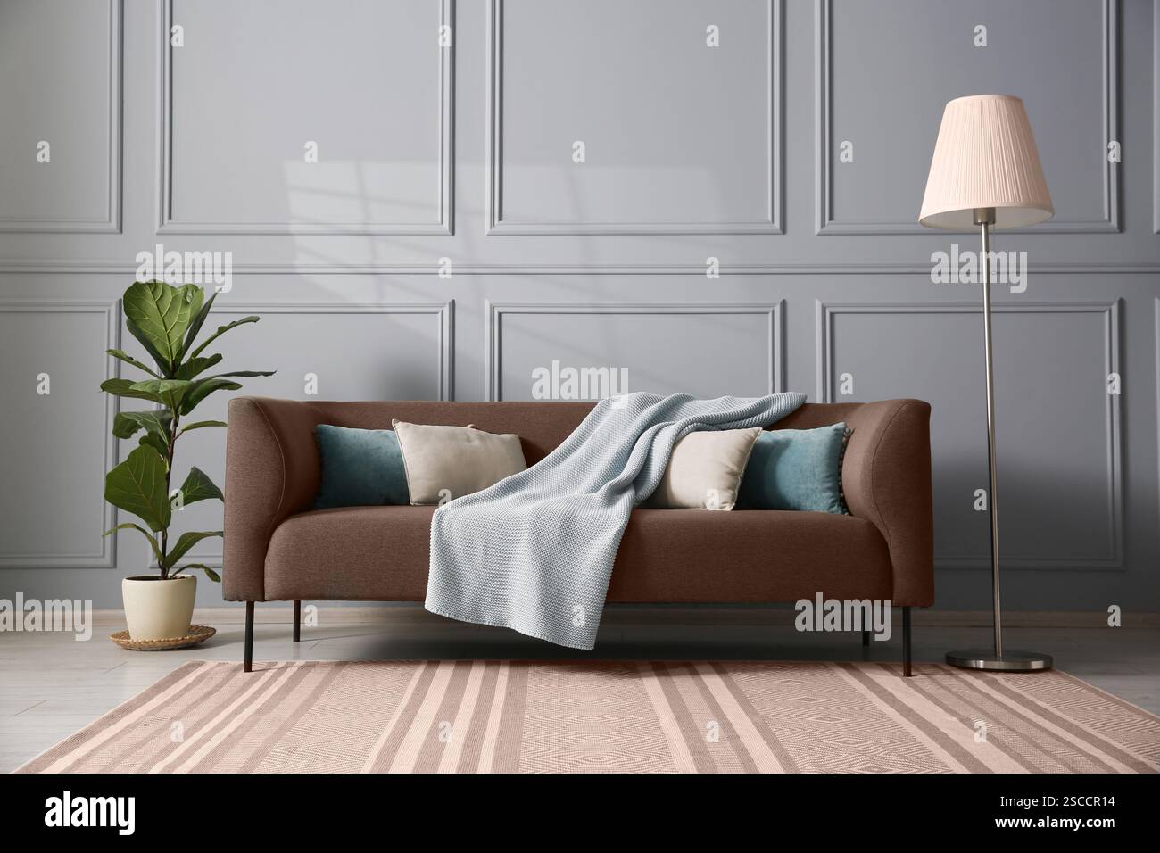 Sofa in mocha mousse shade with pillows, houseplant and floor lamp ...