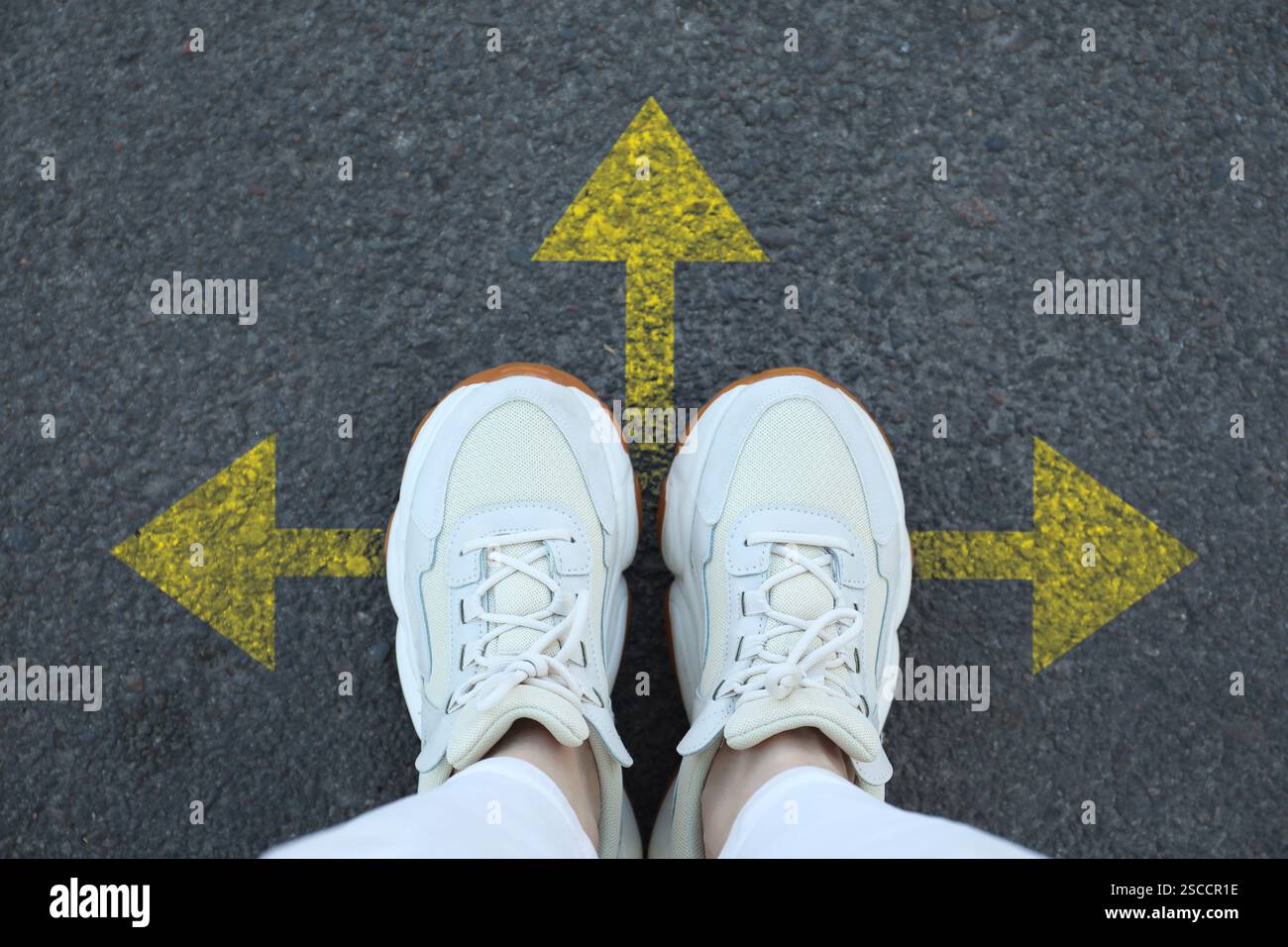 Woman standing near yellow arrows on asphalt road, closeup. Concepts of ...