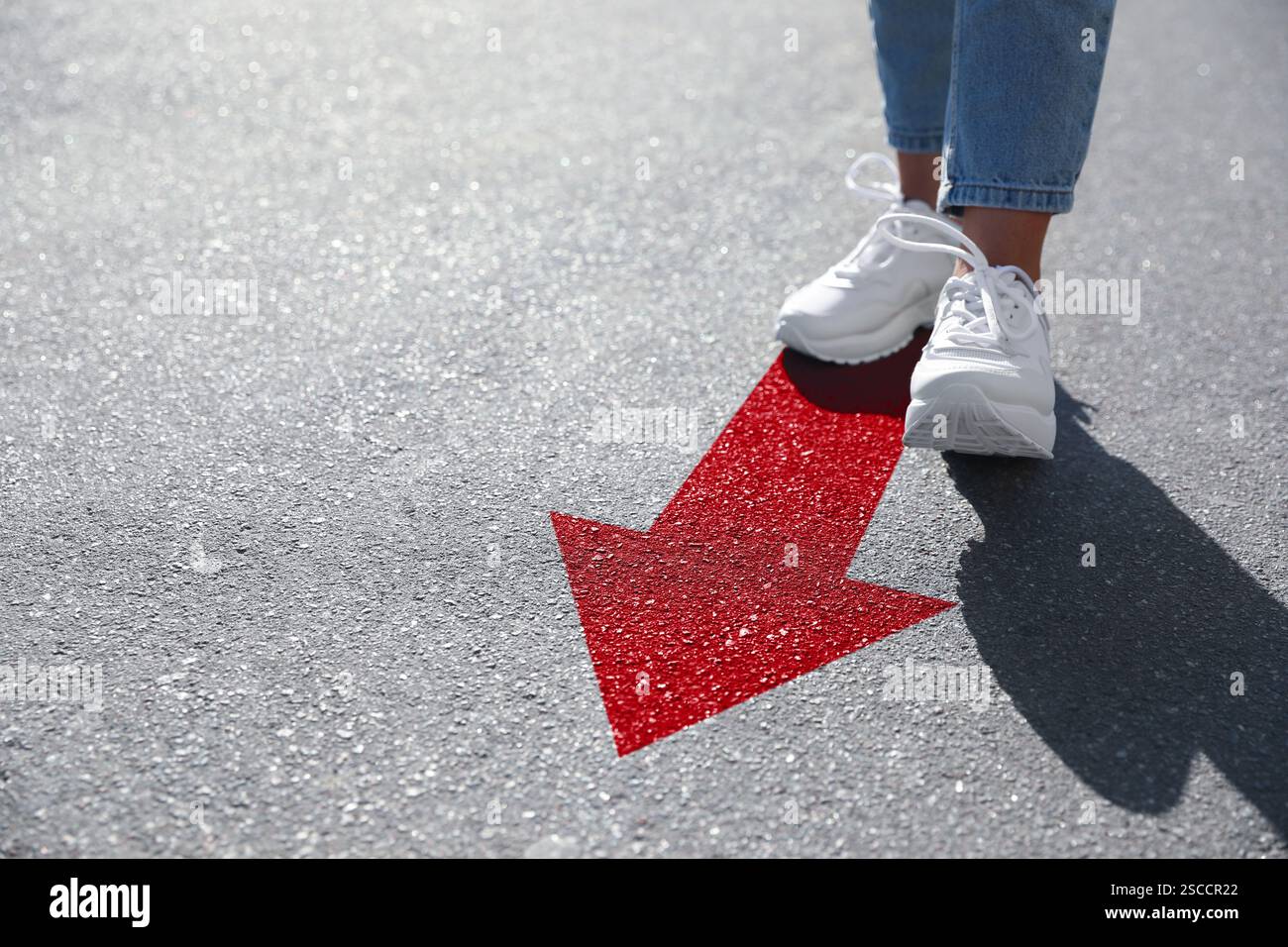 Woman walking on asphalt road with red arrow, closeup. Concepts of ...