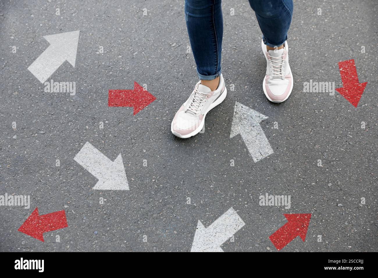 Woman walking on asphalt road with red and white arrows pointing in ...