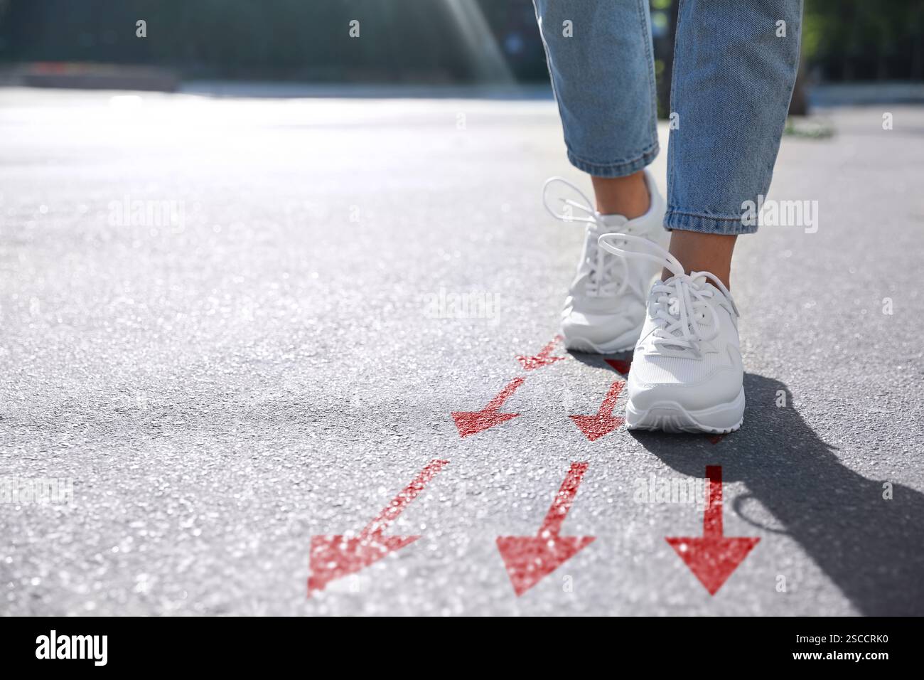 Woman walking on asphalt road with red arrows, closeup. Concepts of ...