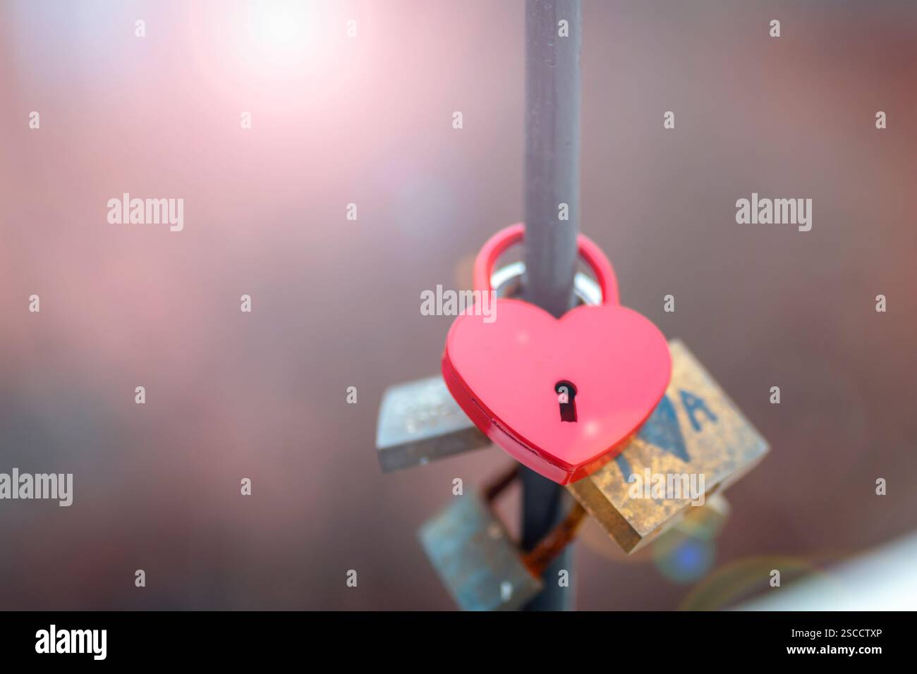 Red heart-shaped padlock attached to a metal rail, symbolizing love and ...