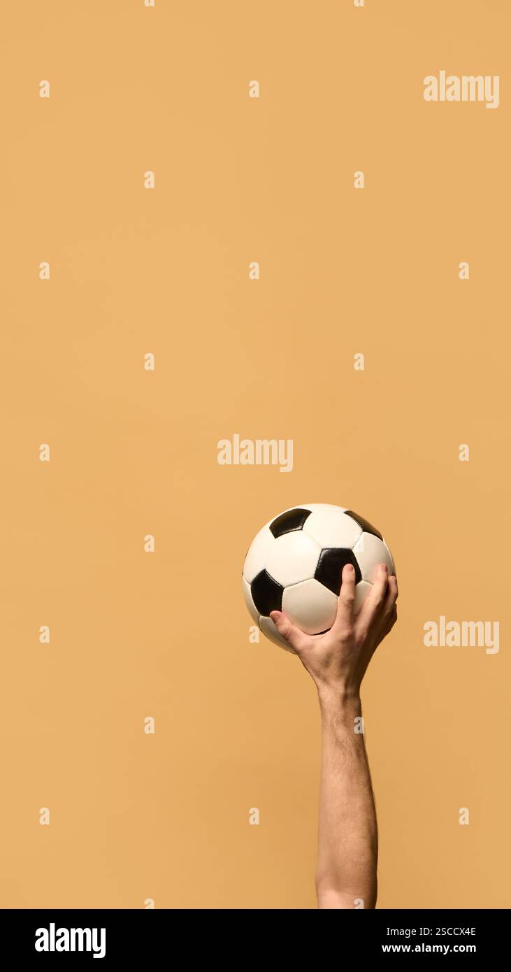 Hand gripping soccer ball high, fingers pressing against black-and ...