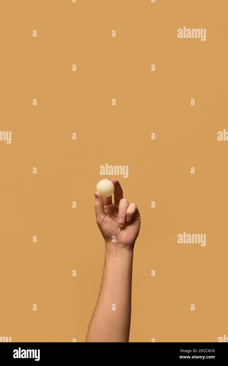 Hand holding small white ping pong ball between fingers, highlighting ...