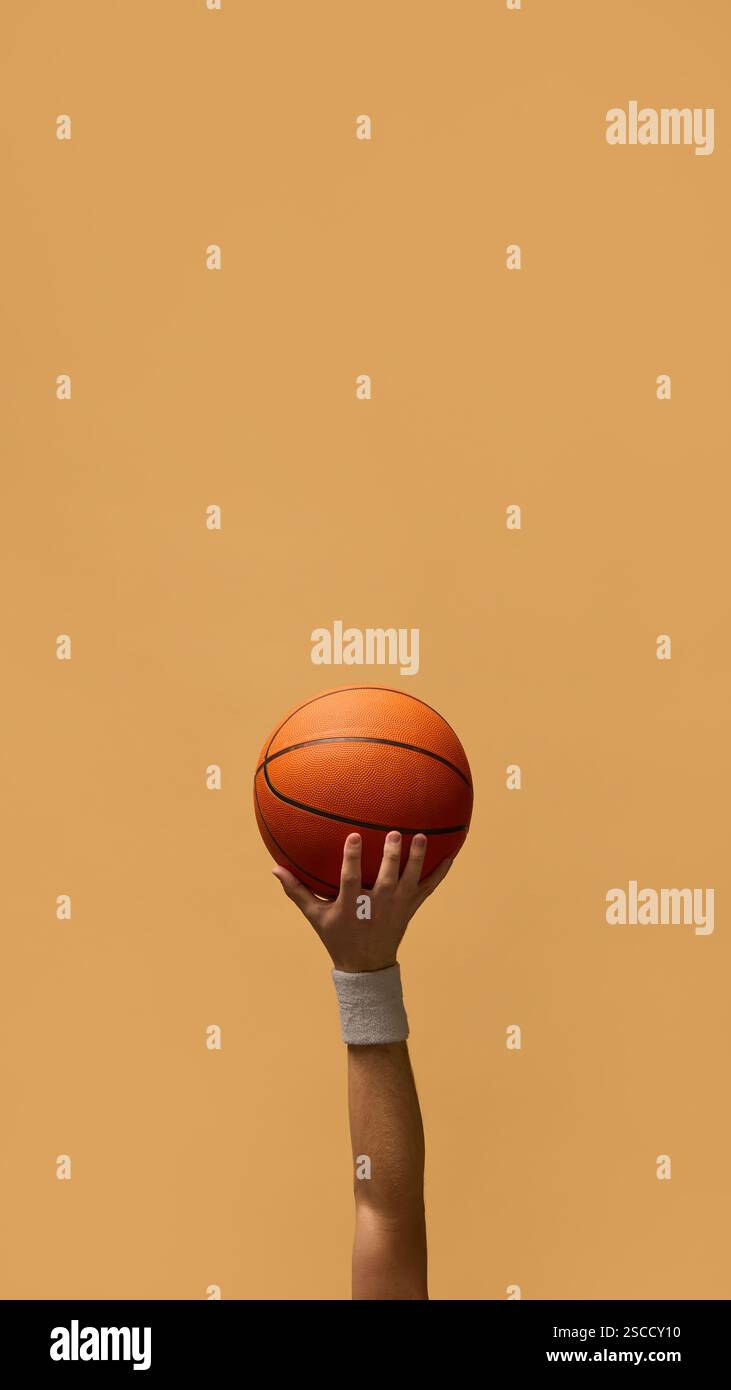Hand lifting orange basketball with fingers spread wide, emphasizing ...