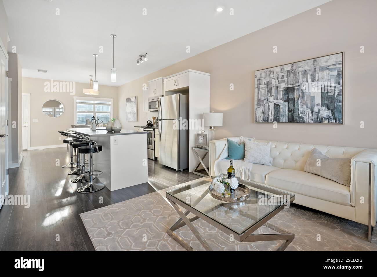 A modern living room with a white couch, coffee table, and a kitchen ...