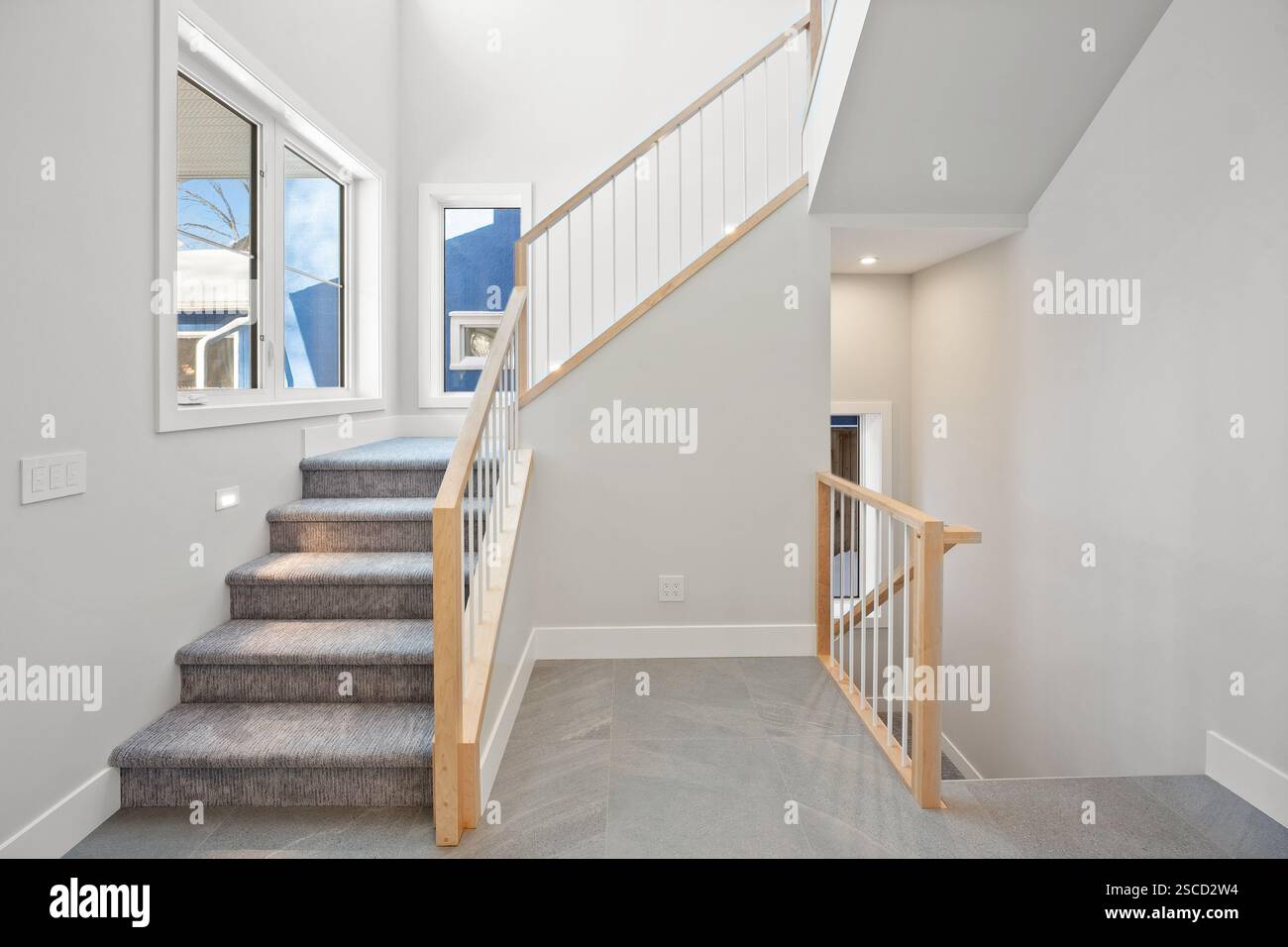 A staircase with a wooden railing and a carpeted landing. The staircase ...
