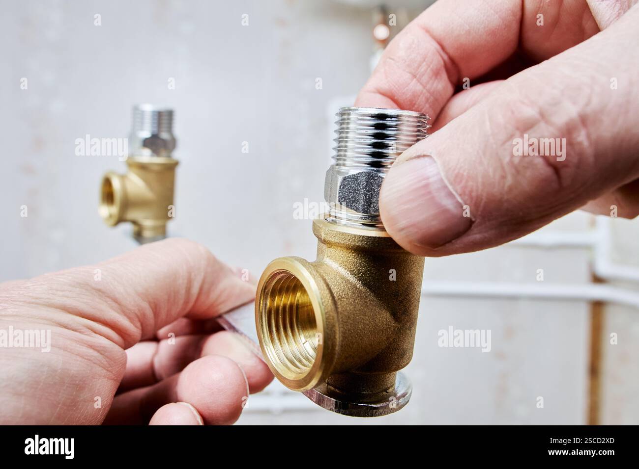 Tightening threaded pipe fitting onto brass connector Stock Photo - Alamy