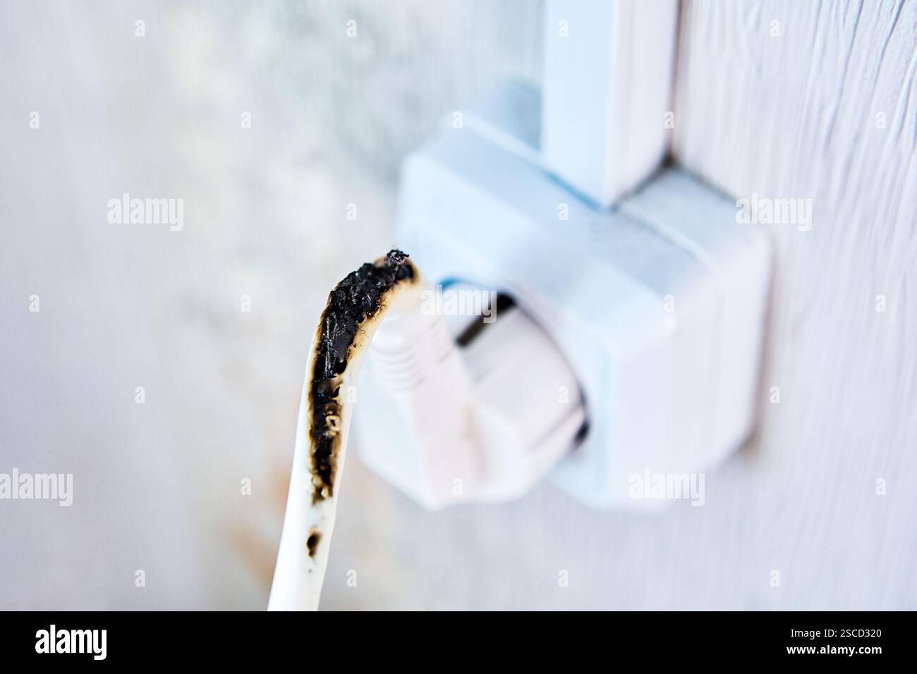 Damaged power cable with scorch marks near an outlet Stock Photo - Alamy