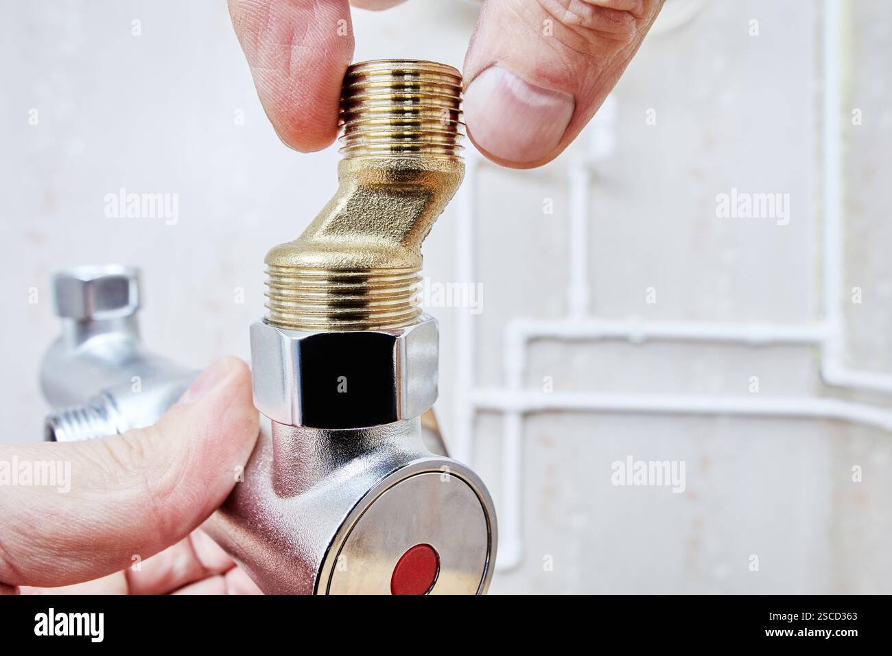 Hands assembling plumbing system with dog leg reducer and metal valve ...