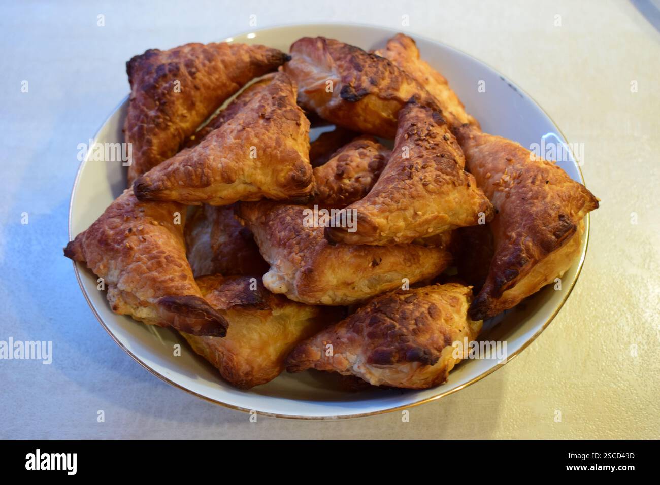 A bowl filled with several pieces of triangular, golden-brown pastries ...