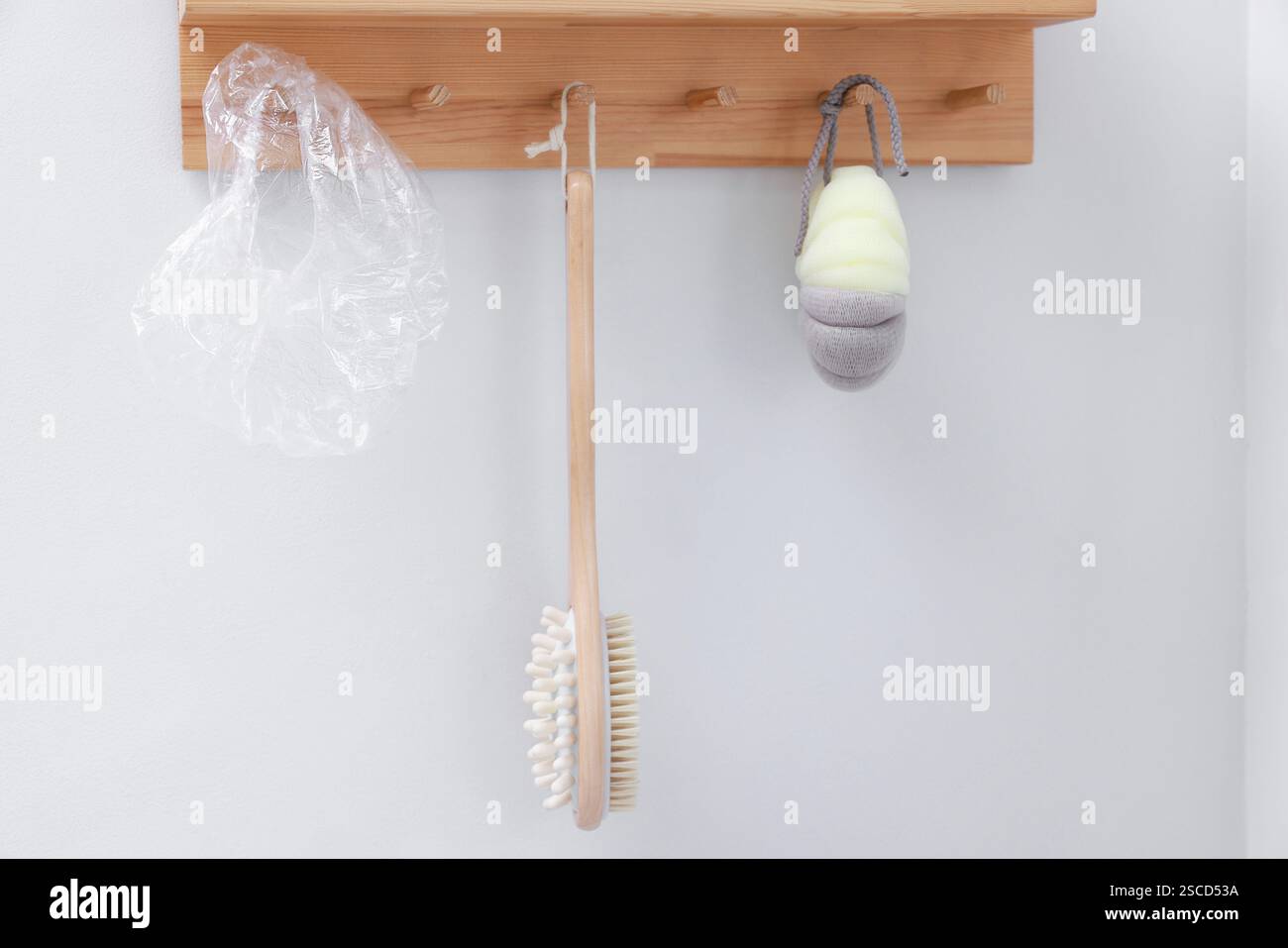 Shower cap, brush and mesh sponge on rack indoors Stock Photo - Alamy