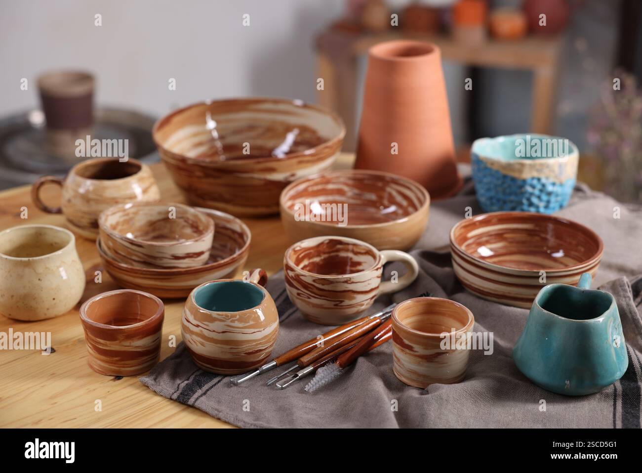 Different beautiful pottery and set of clay crafting tools on table ...