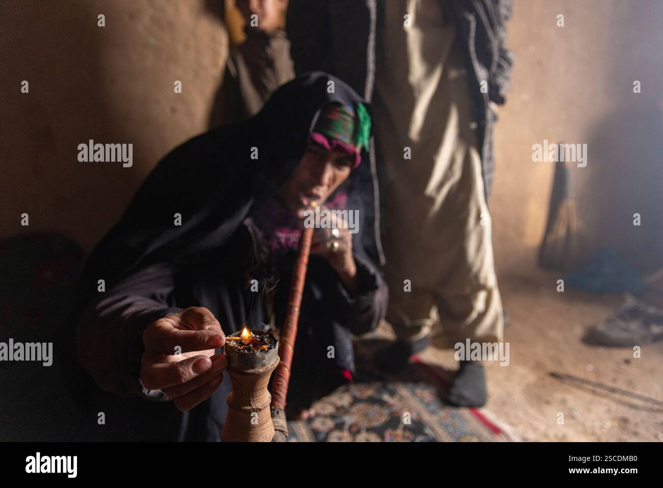 An elderly Afghan woman prepares a Chilim, a traditional hookah filled ...