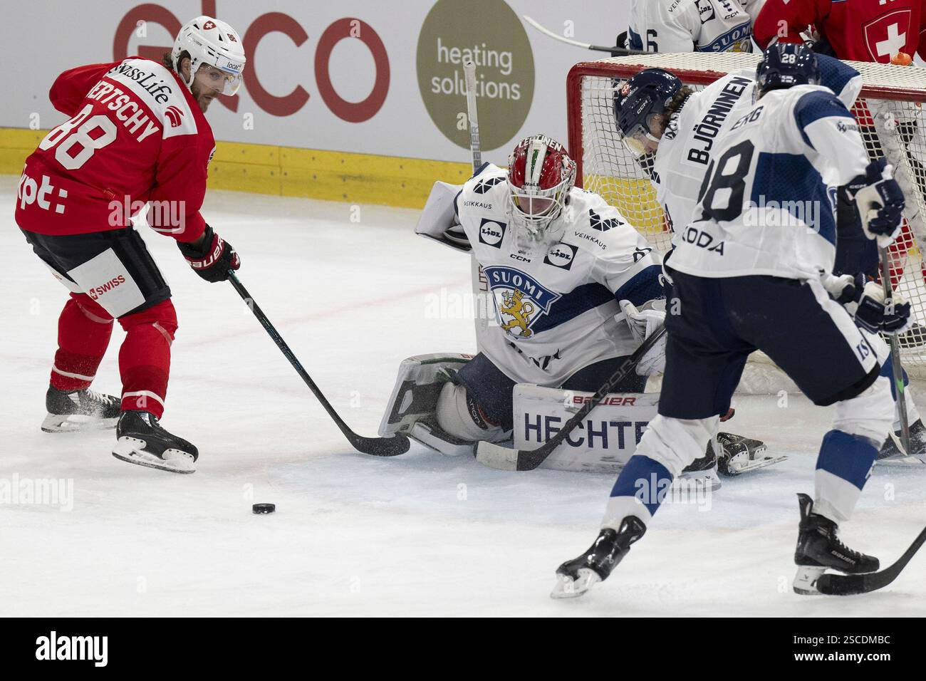 Switzerland's Christoph Bertschy, left, in action against Finland's goalkeeper Lassi Lehtinen ...
