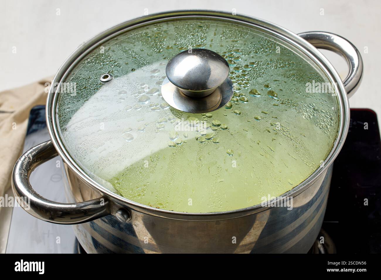 a pot with a closed, dewy lid on the stove. process of making dinner ...