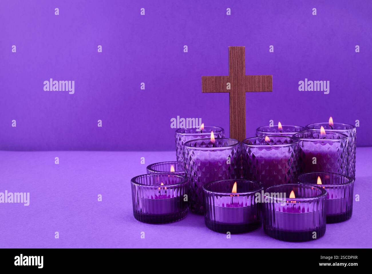 Lent Symbolism. Cluster of lit candles with a cross on a purple ...
