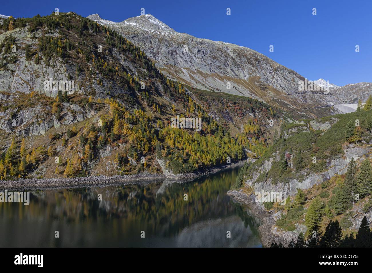 The Galgenbichl reservoir with a mountain forest in fall foliage on a ...
