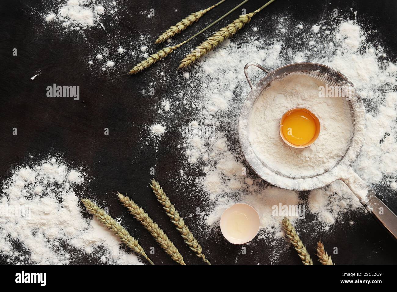 Flour with raw egg, sieve and wheat ears. Baking process background ...