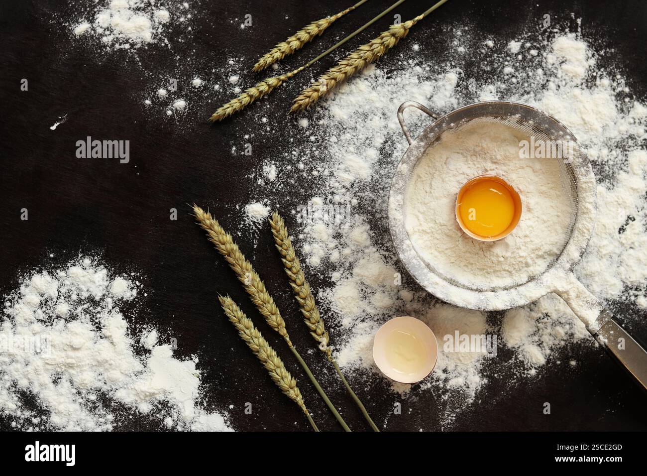 Flour with raw egg, sieve and wheat ears. Baking process background ...