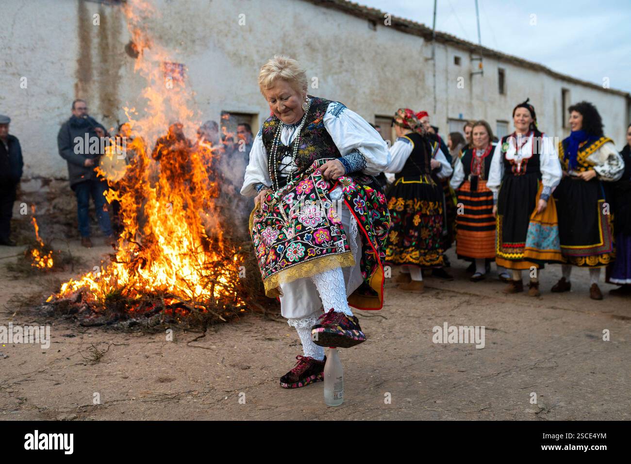 A woman dressed in typical regional costume near a bonfire during the ...