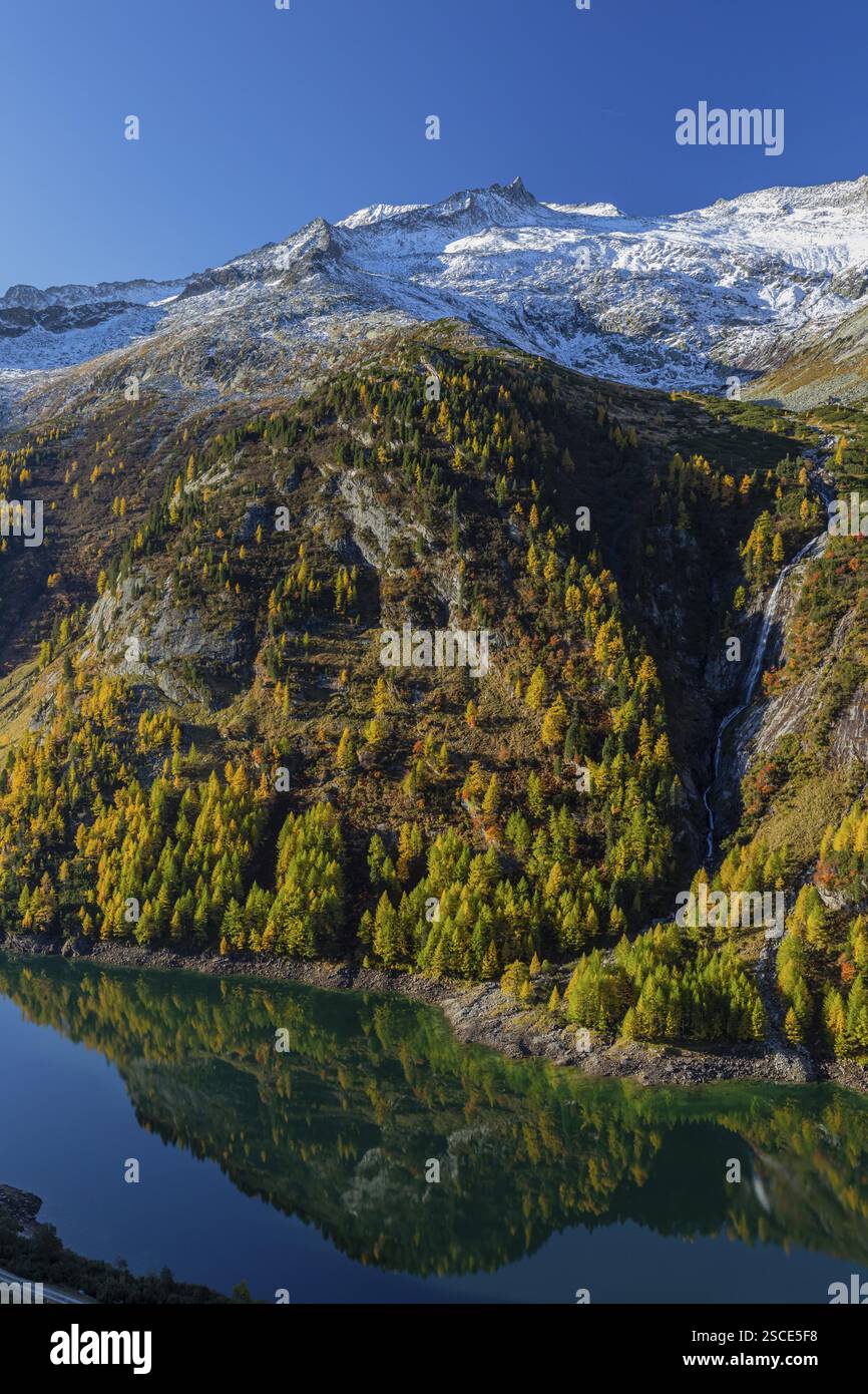 The Galgenbichl reservoir with a mountain forest in fall foliage on a ...