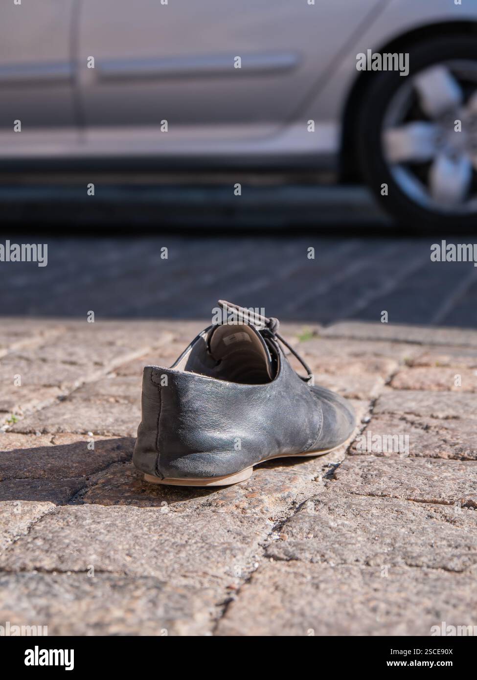 A worn leather shoe rests on a cobblestone surface, revealing signs of ...