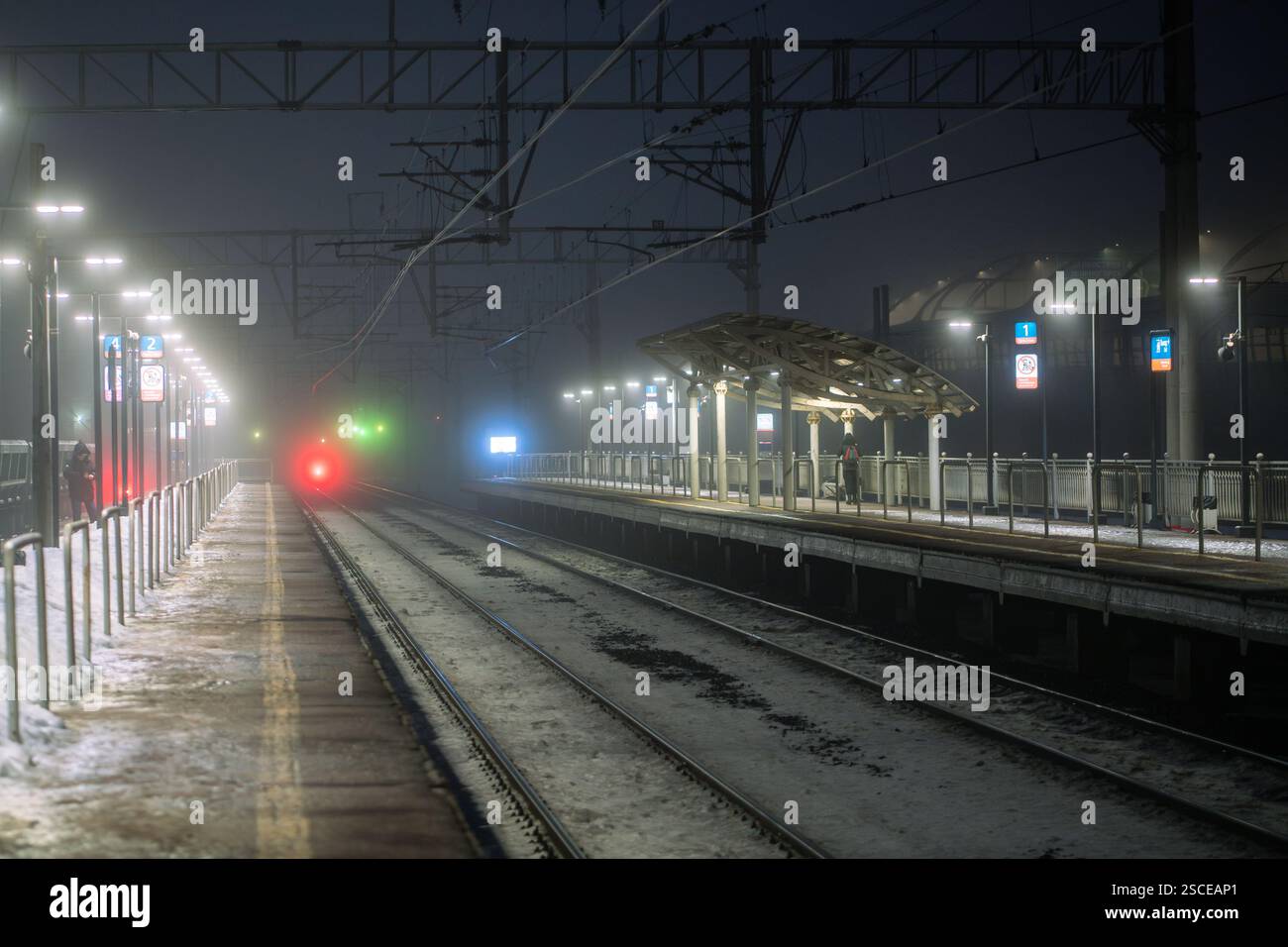 Dense fog covers train station platform with faint halo of lights on ...