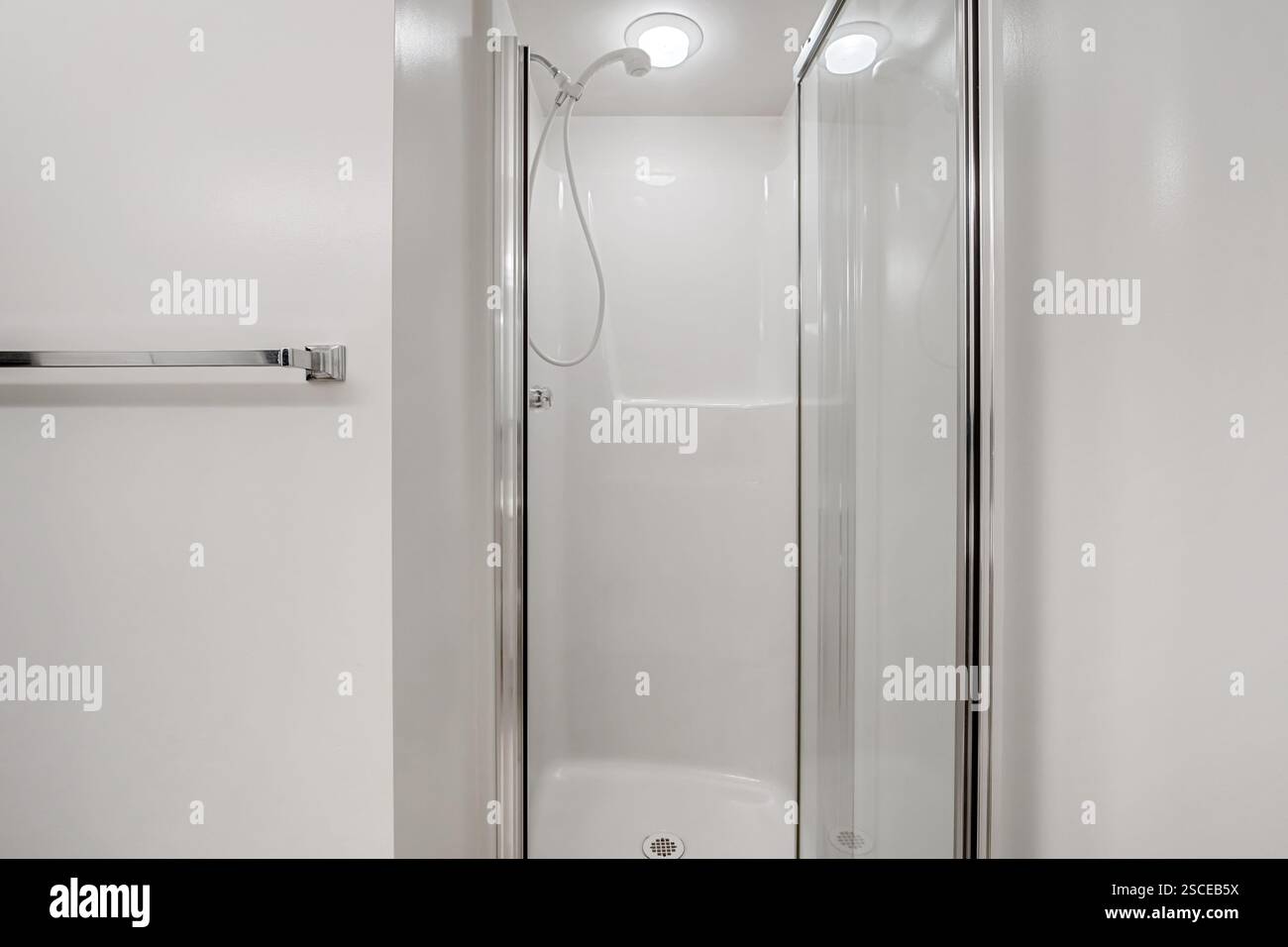 A shower stall with a shower head and a towel rack. The shower stall is ...