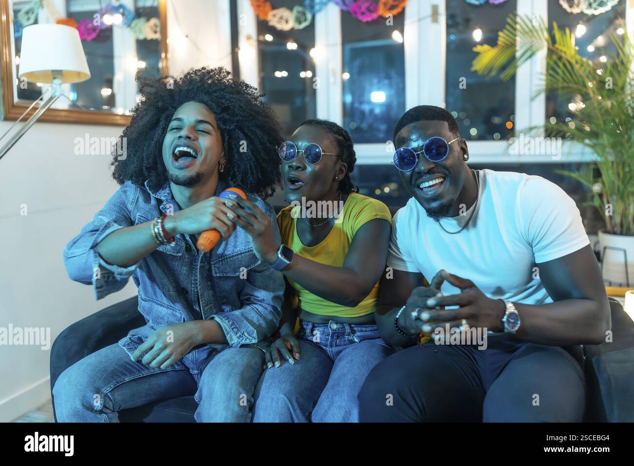 Excited multi-ethnic young friends singing karaoke together during ...