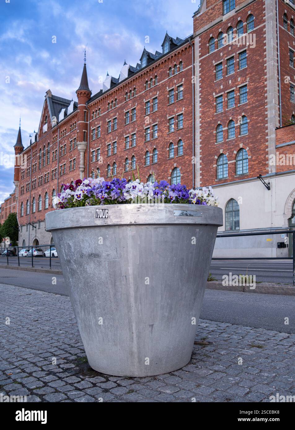A large metal planter filled with colorful flowers is placed on a ...