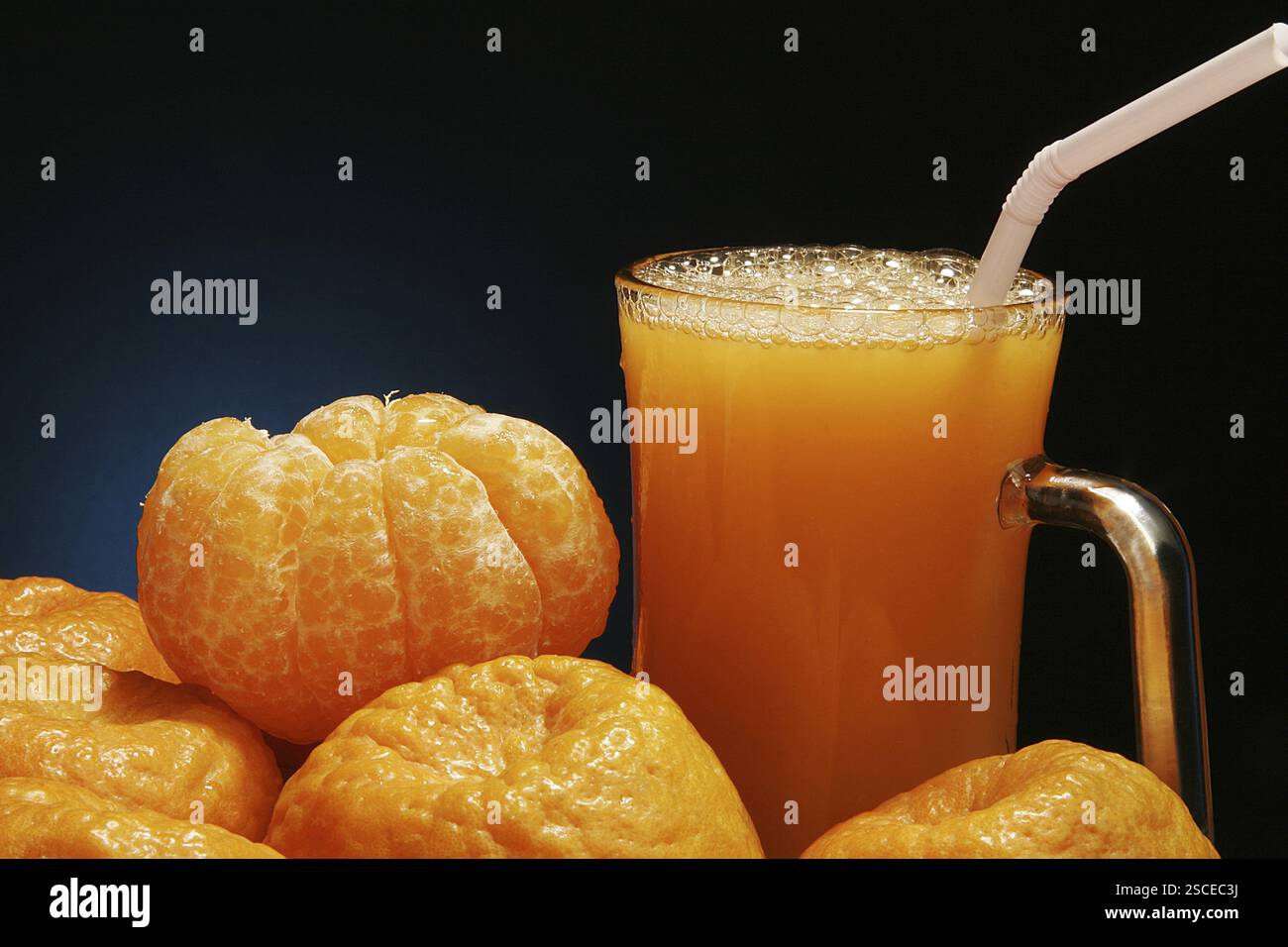 Fruit, one pealed and other unpeeled oranges with glass of orange juice ...