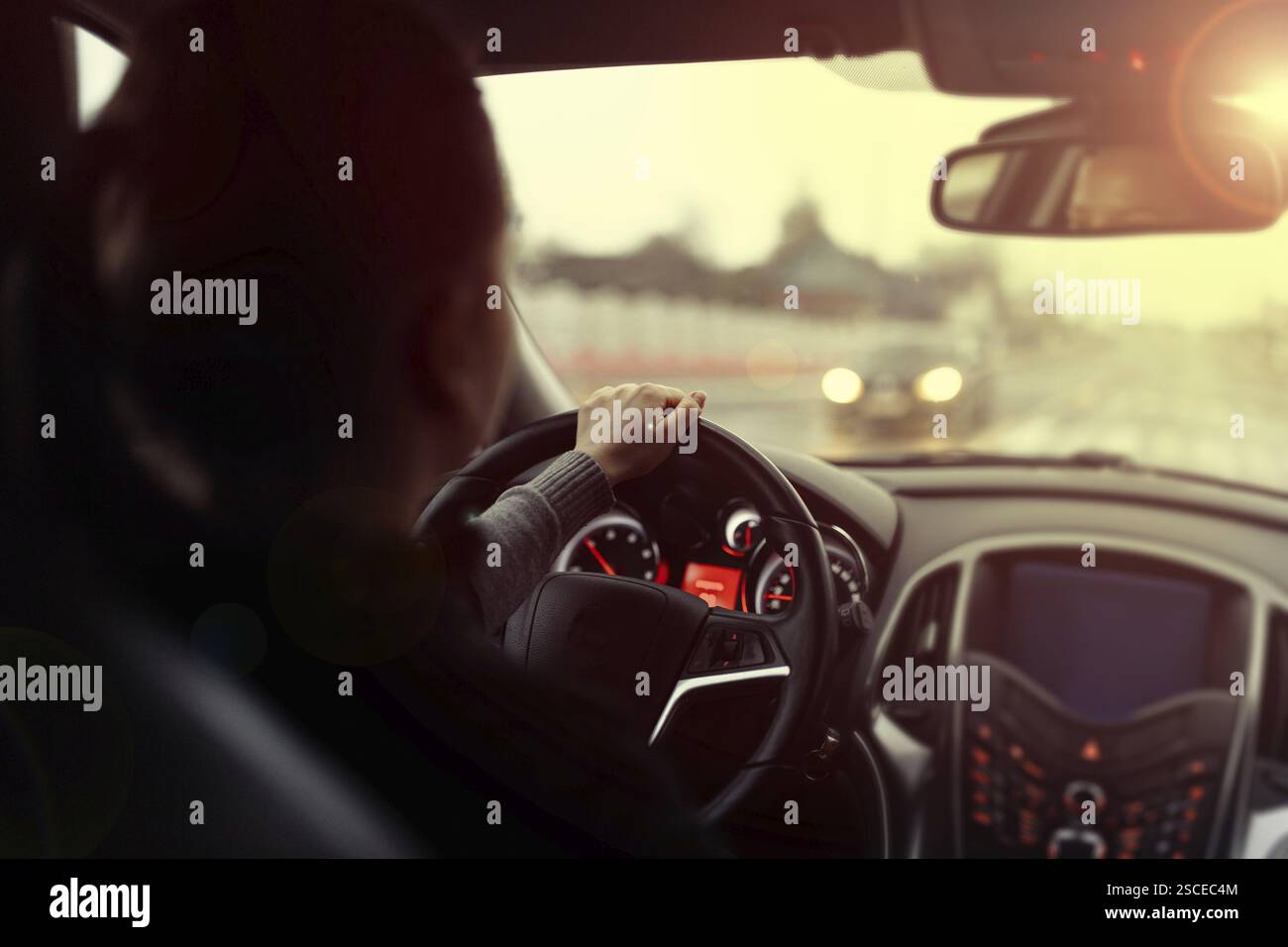 Person driving at dusk, dashboard illuminated, creating a focused mood ...