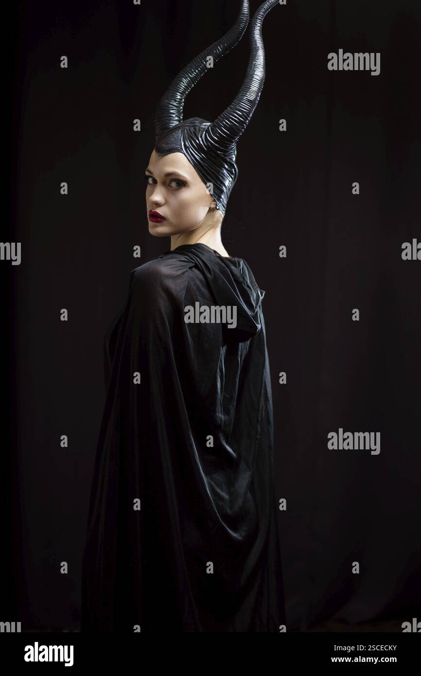 An enigmatic figure with a horned headpiece looking over the shoulder ...