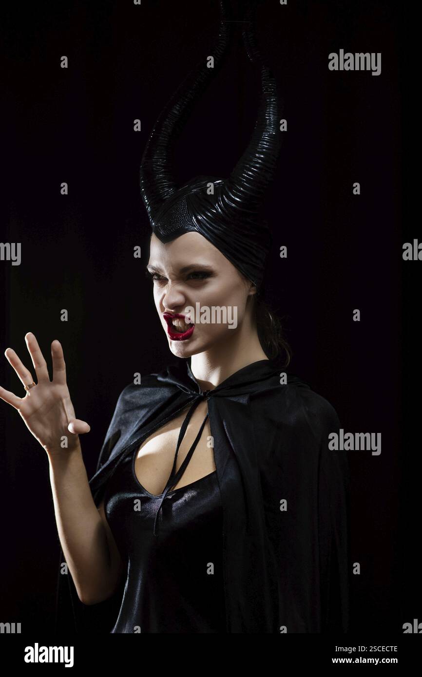 A fierce woman in costume with horns and intense expression, making a ...